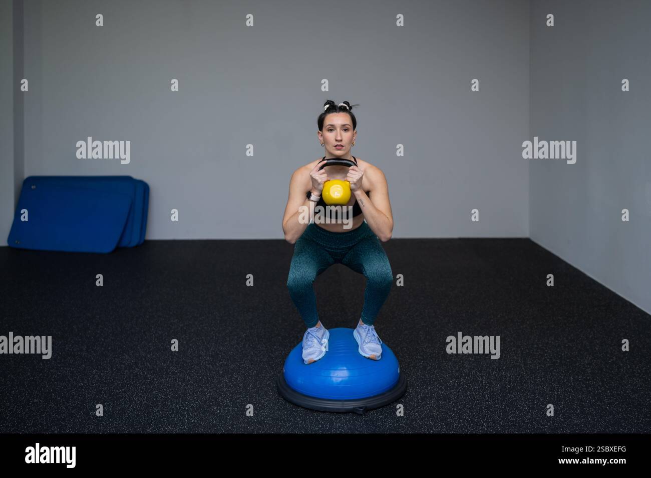 Young athletic woman performing squats with a kettlebell while ...