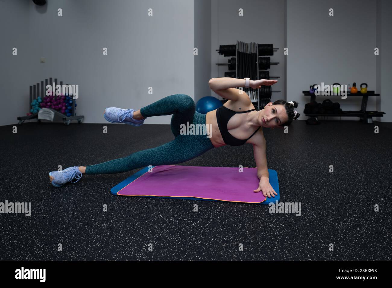 Young sportswoman practicing side plank pose variation on purple mat in ...