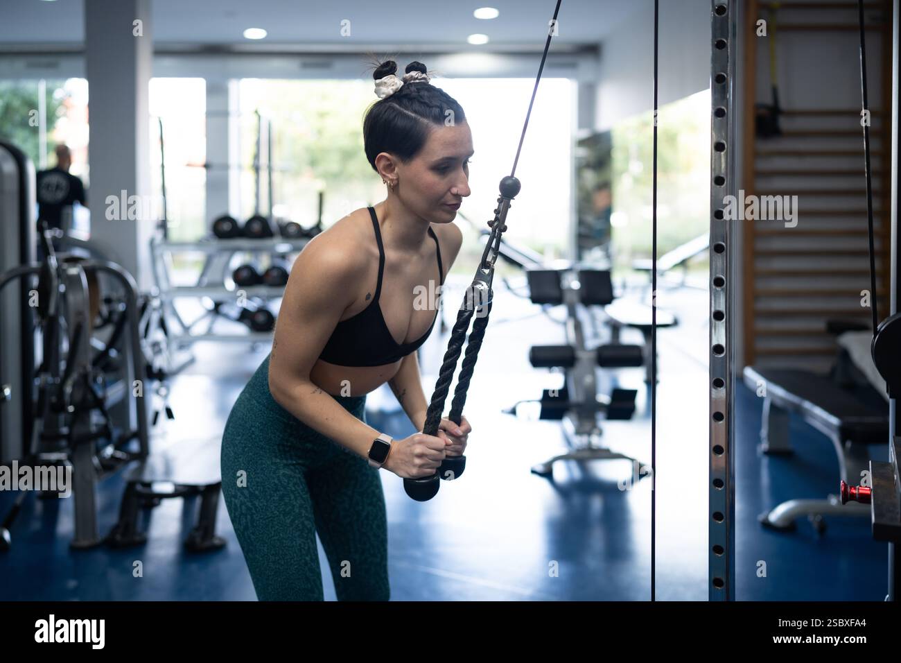 Strong female athlete performing triceps pushdown exercise using cable ...