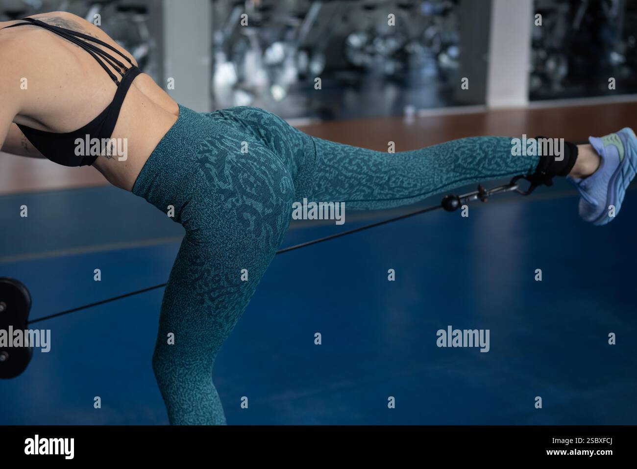 Female athlete performing cable leg extensions targeting glute muscles ...