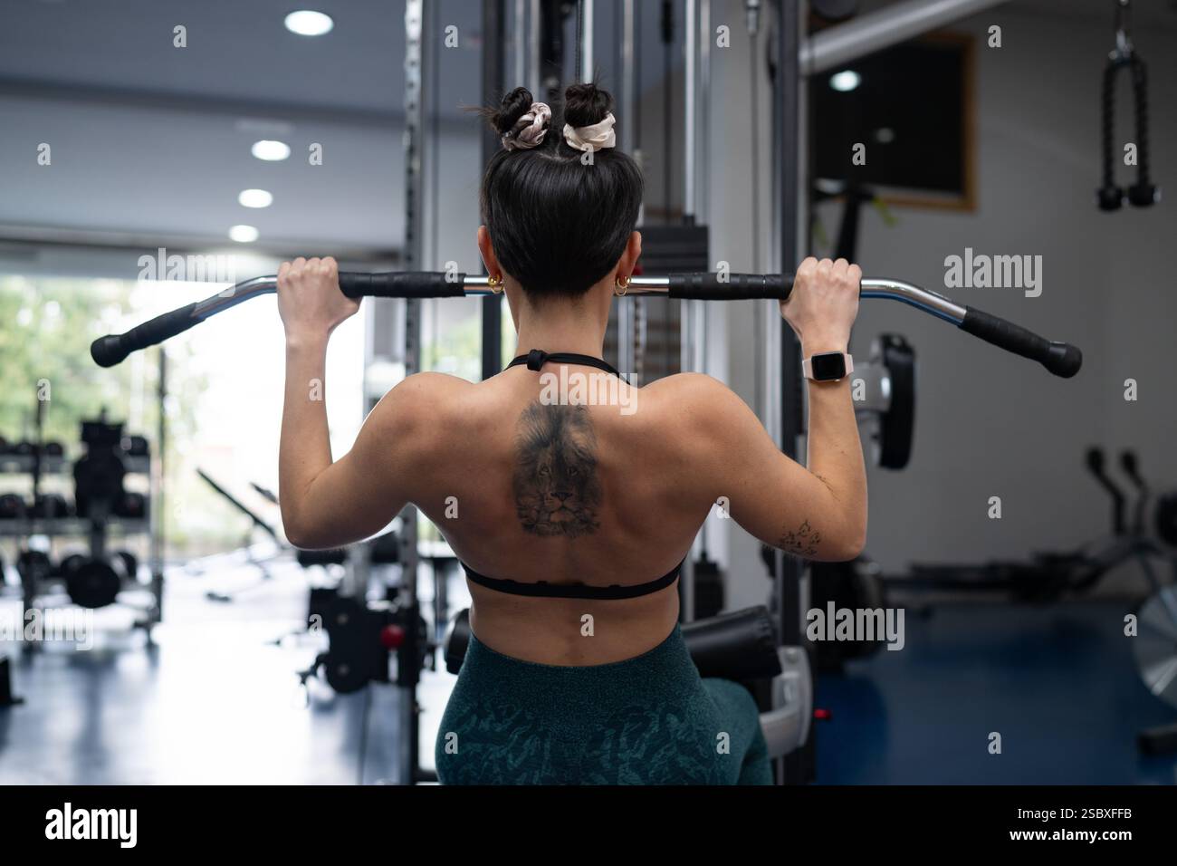 Strong female athlete exercising back muscles using lat pull down ...