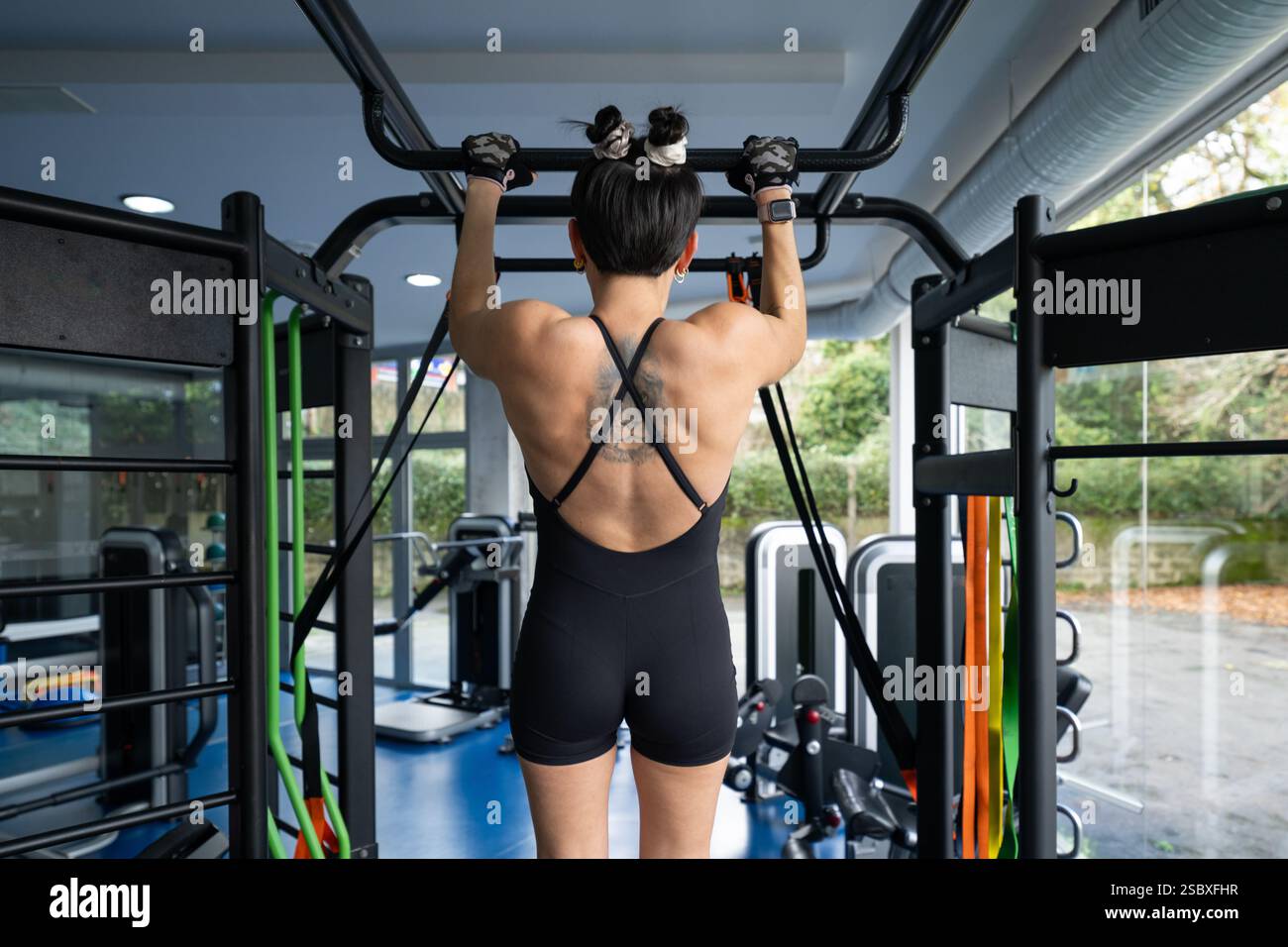 Strong female athlete exercising back muscles by doing pull ups on a ...