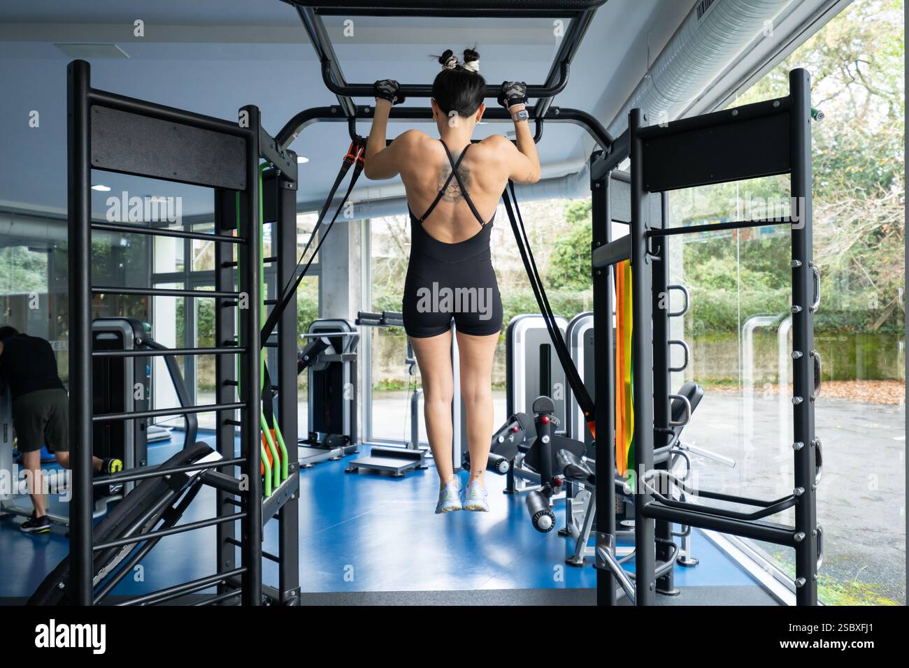 Strong female athlete performing pull ups on a bar in a modern, well ...
