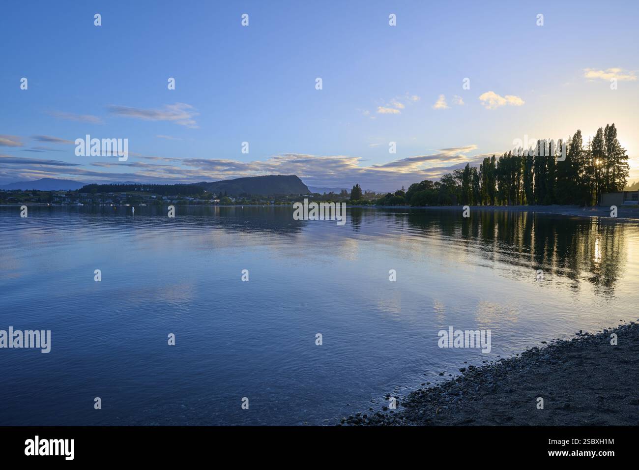 Clear lake with trees on the shore, sunrise and cloudy sky, calm ...