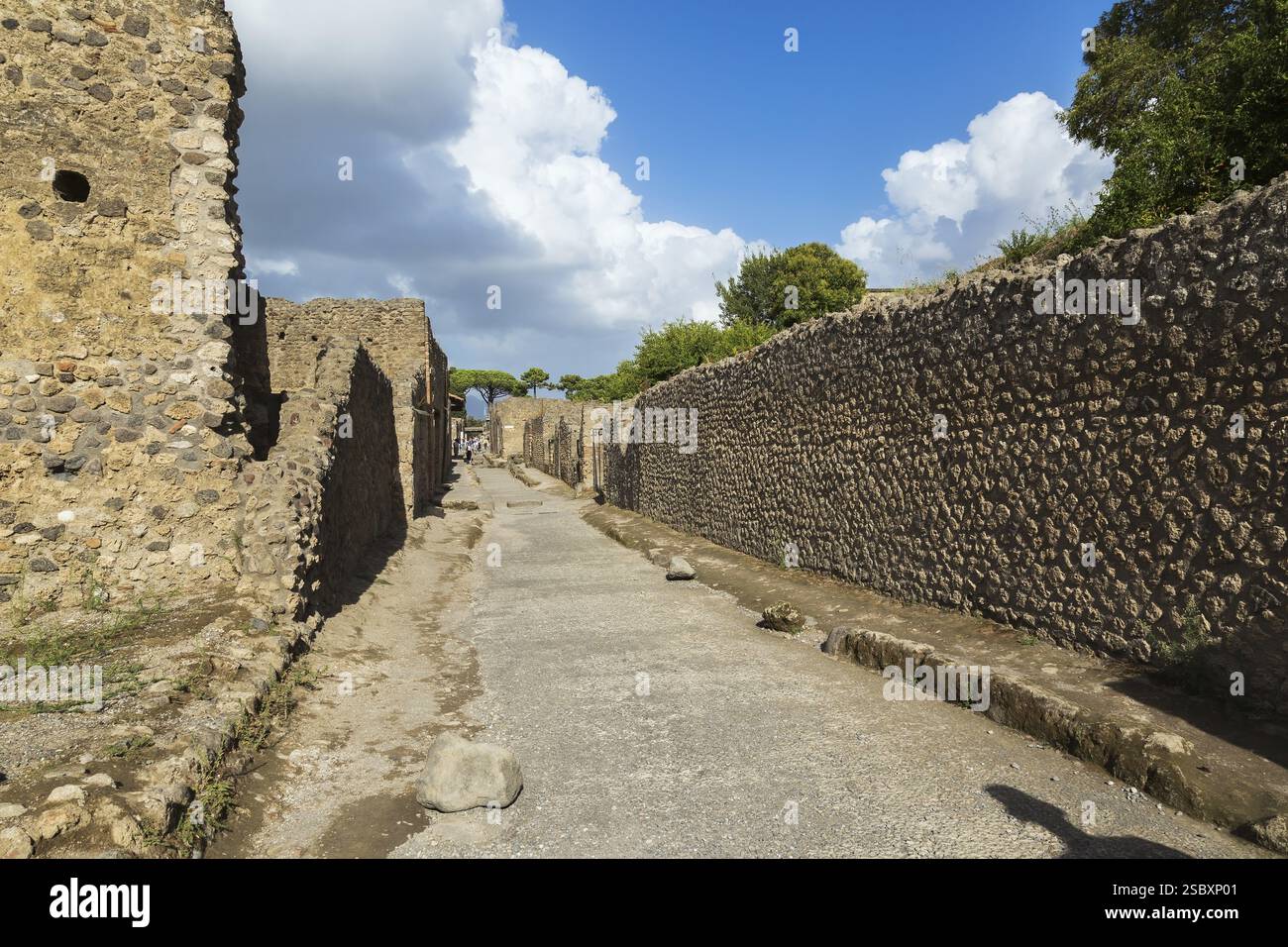 Long compacted crushed stone paved street with sidewalk and old stone ...