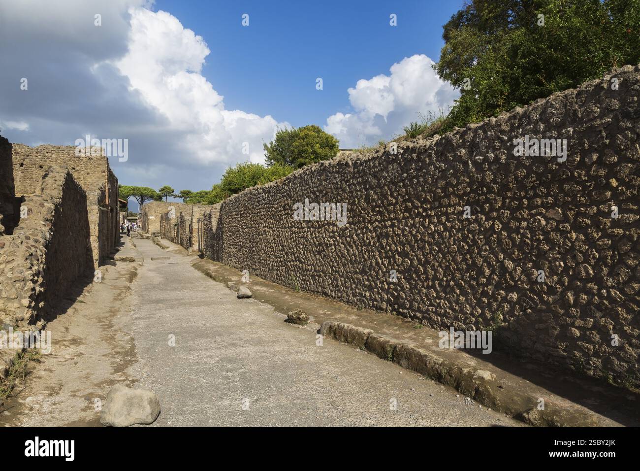 Long compacted crushed stone paved street with sidewalk and old stone ...