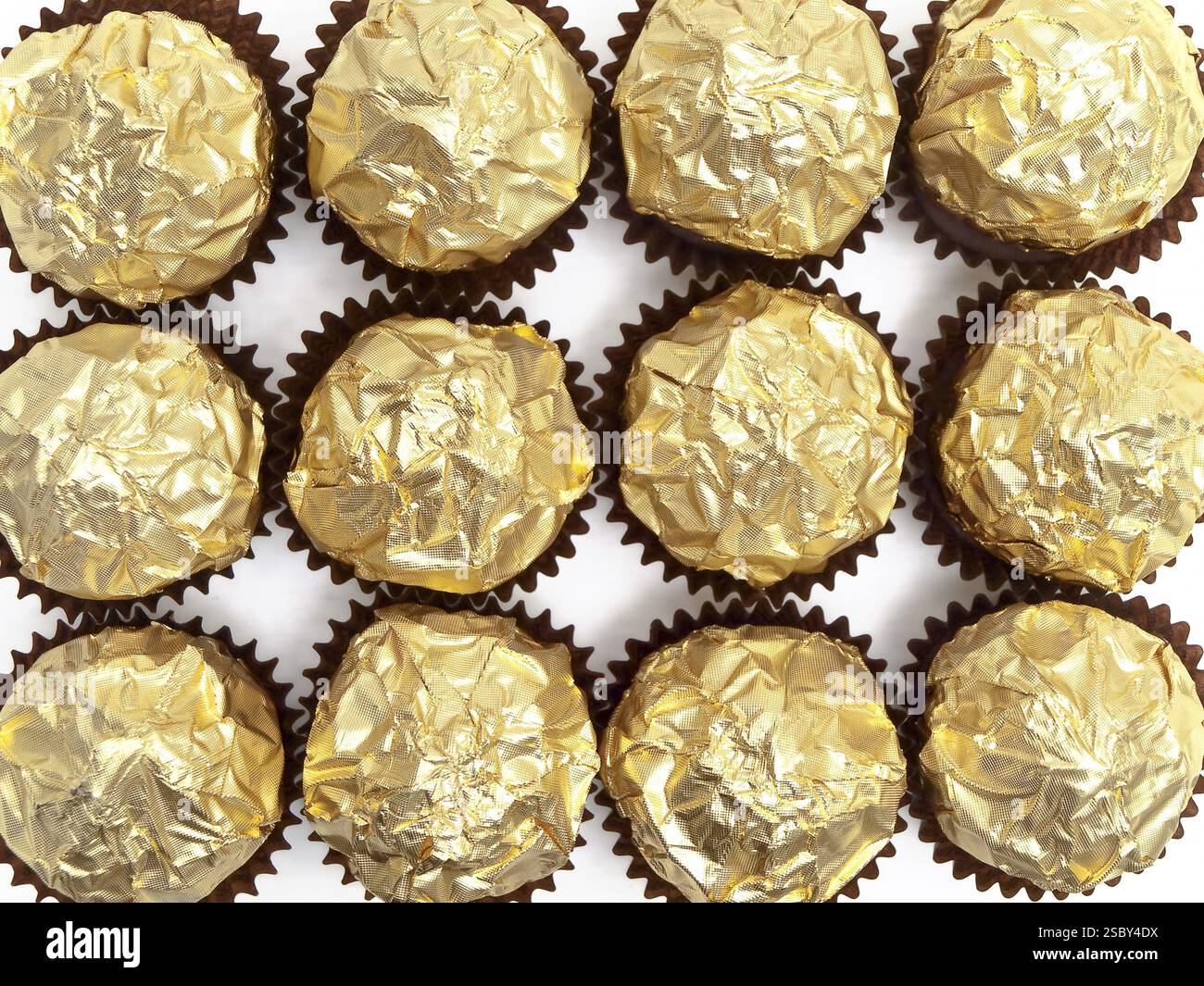 Rows of candies in gold paper over the white background Stock Photo - Alamy