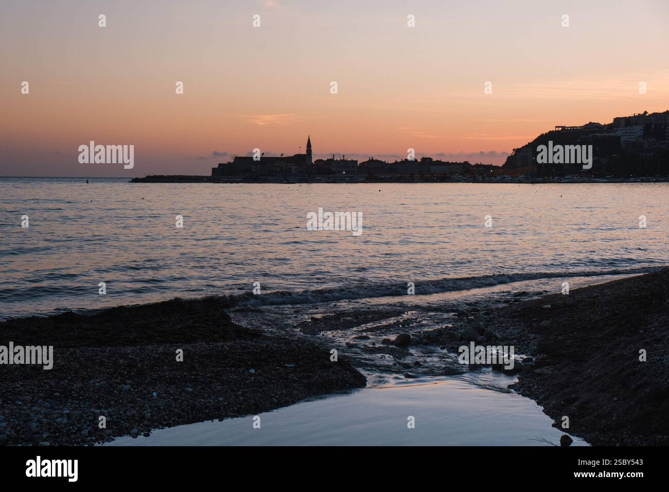 Mediterranean beach at sunset, river meets the sea, reflections, old town in background Stock ...