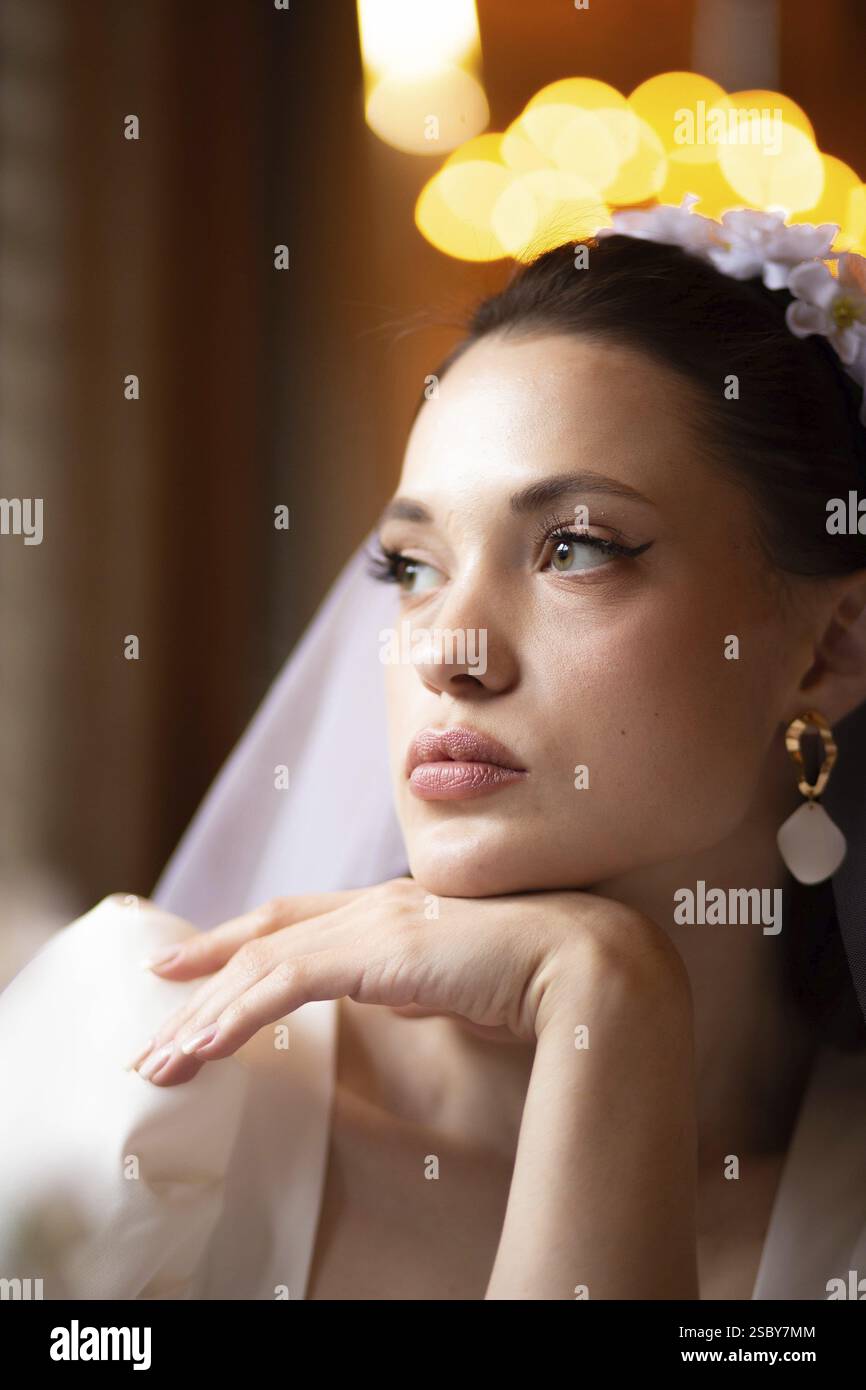 Bride gazing away under romantic lighting with a soft bokeh effect ...