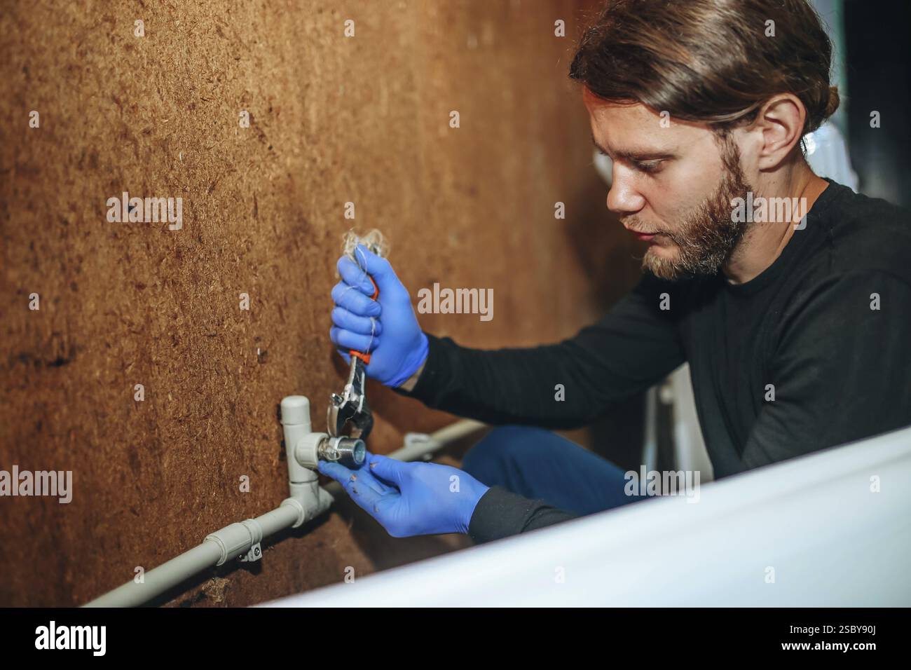 Person using a wrench on a pipe connection while wearing gloves Stock ...