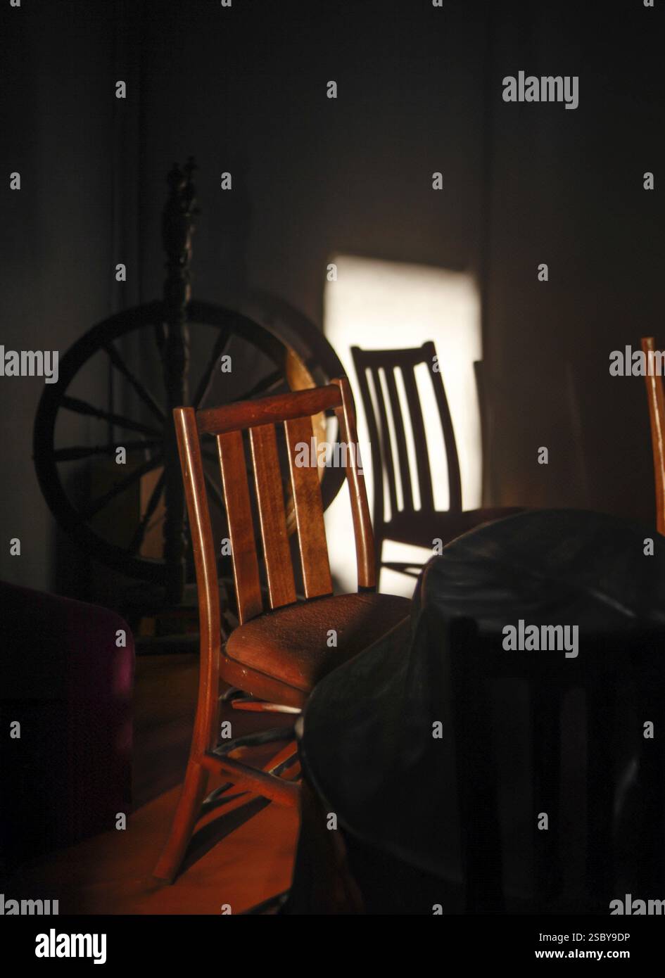 Dimly lit room featuring wooden chairs and a wheel casting intriguing ...