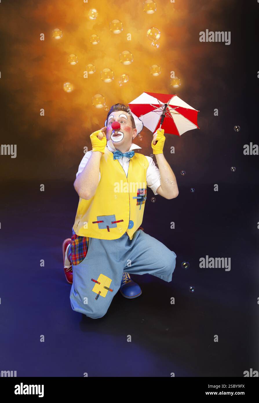 A funny clown with smiling joyful expression, at colored background ...