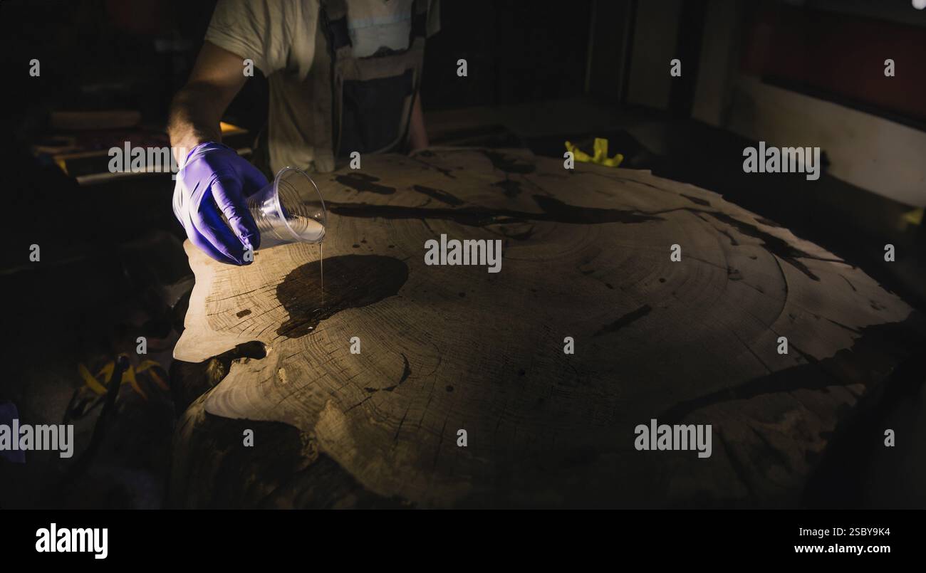 Applying resin on a tree stump with a gloved hand, capturing the ...