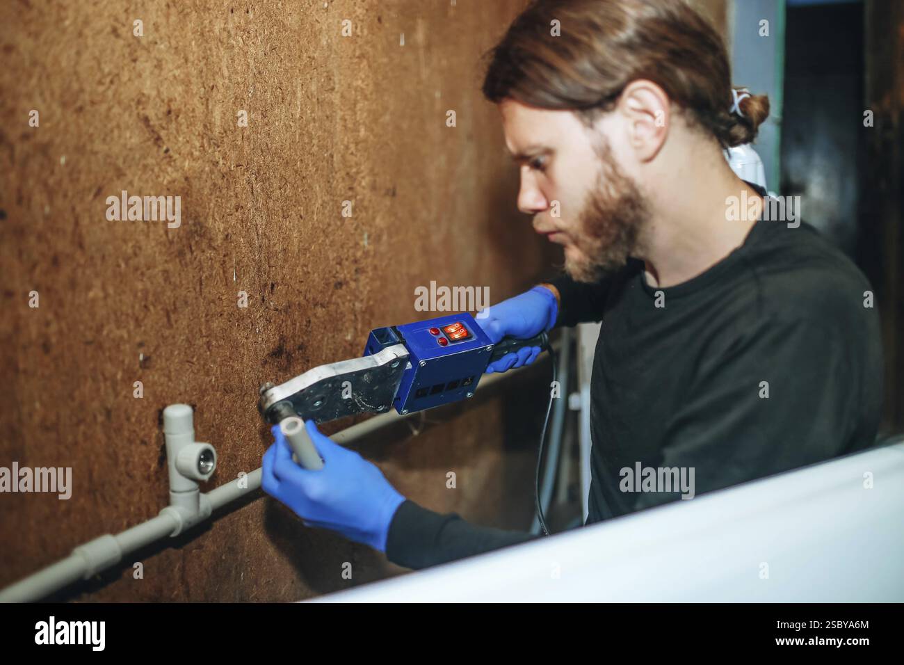 Person using a tool on pipes with focused precision Stock Photo - Alamy