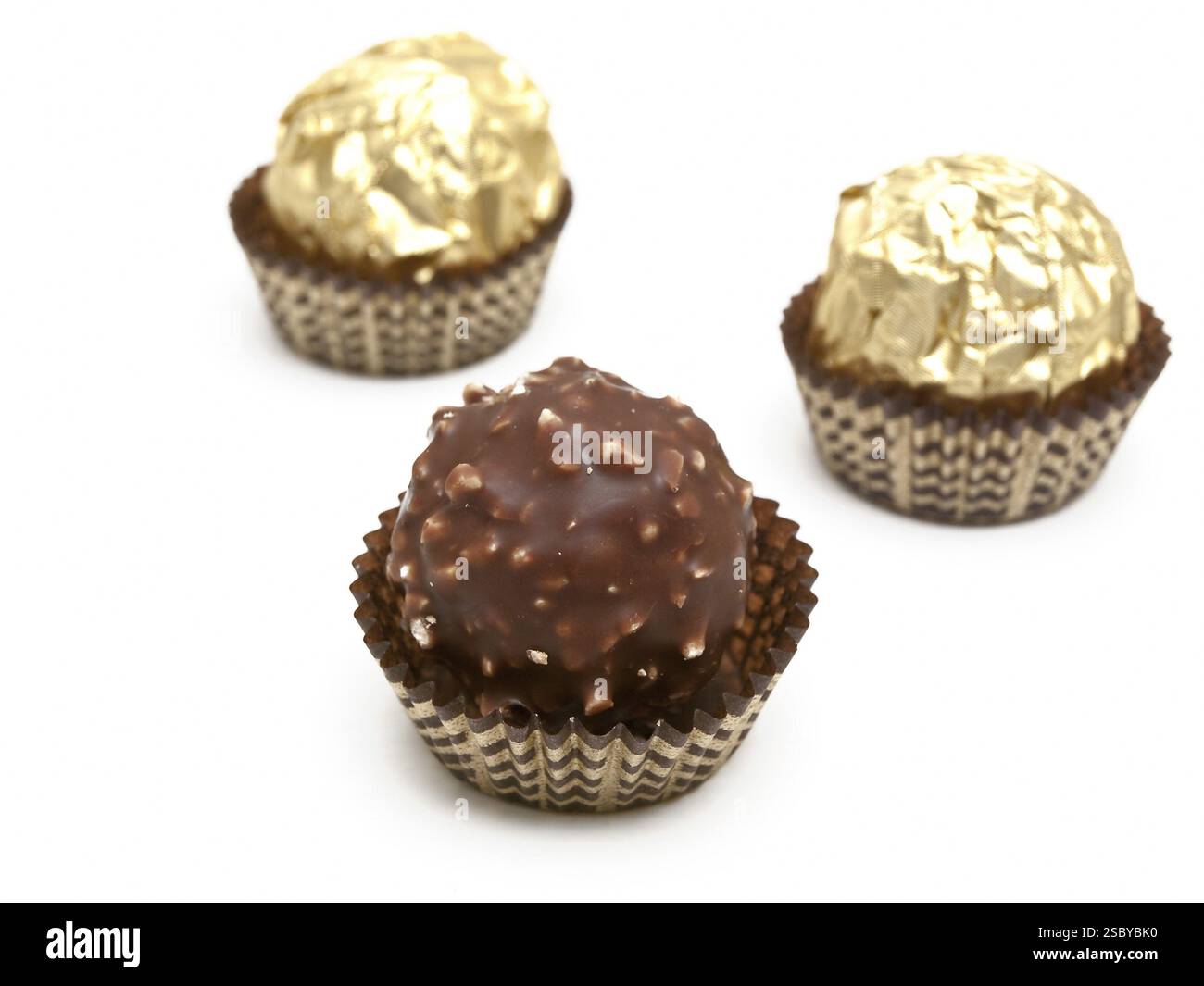 Three candies in gold paper over the white background Stock Photo - Alamy