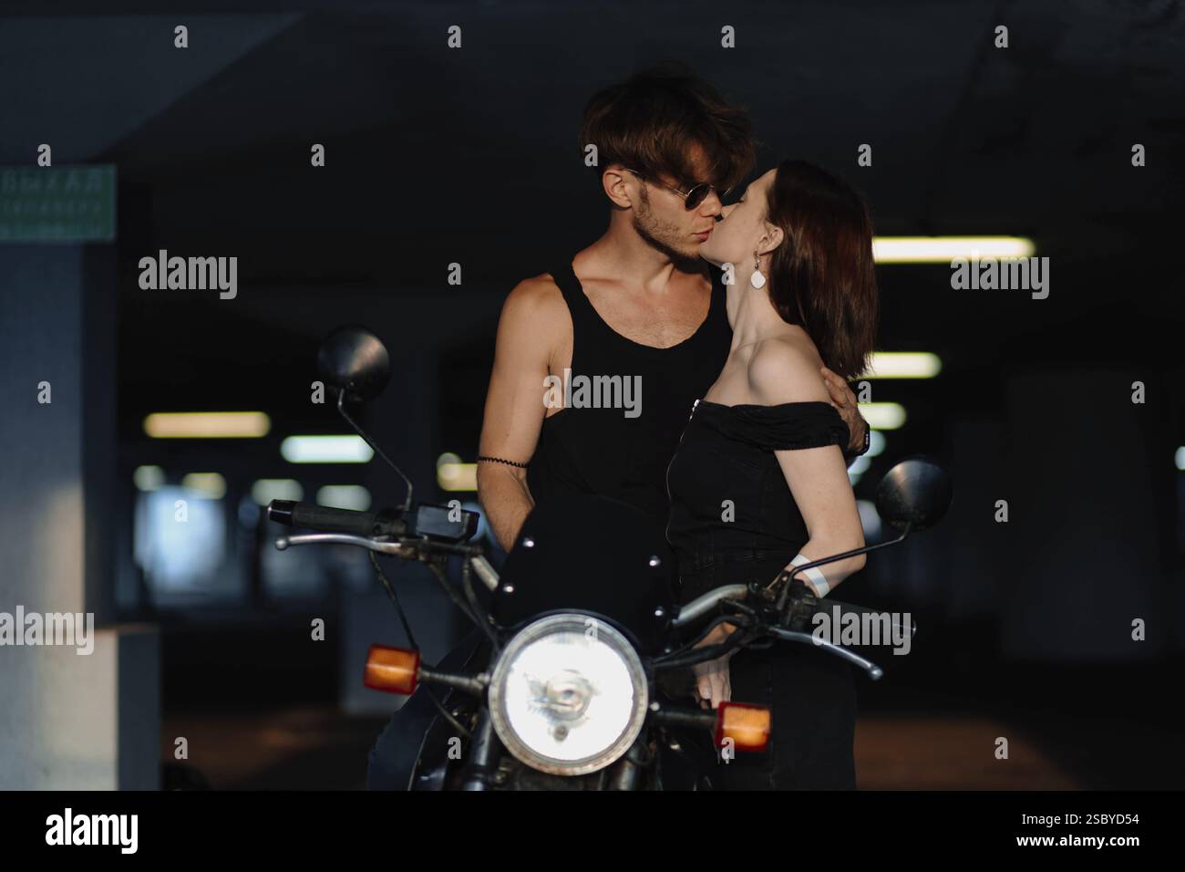 A couple shares a romantic kiss on a motorcycle in an urban setting at ...