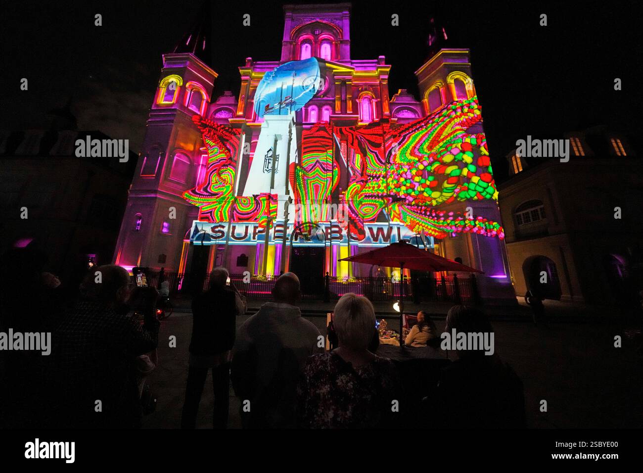 People watch a laser light show projected onto the St. Louis Cathedral ...