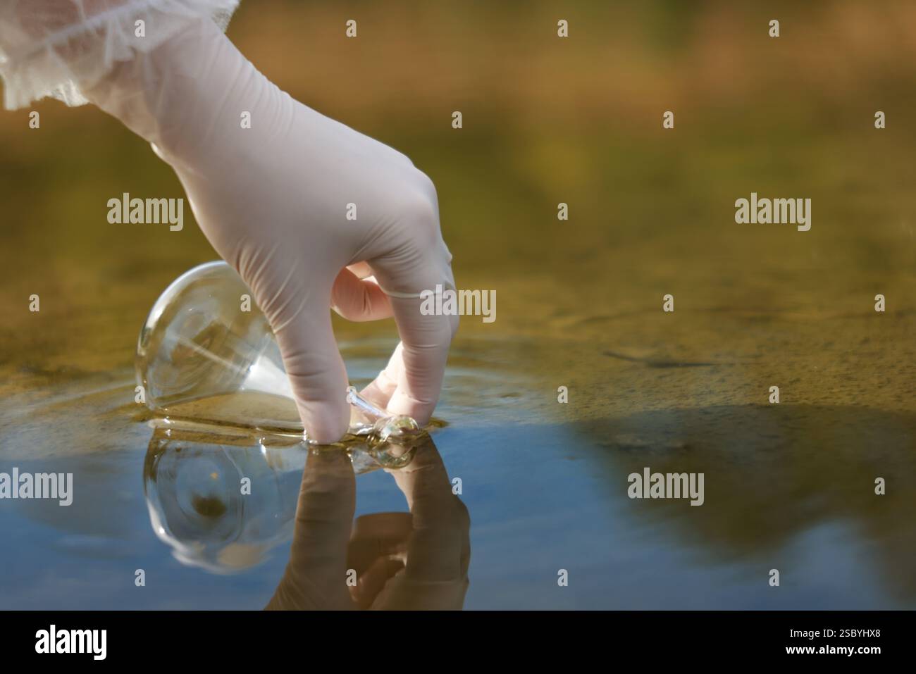 Examination of water quality. Researcher taking water sample from lake ...