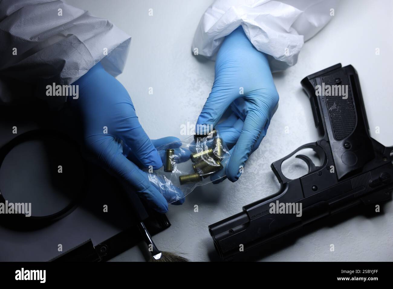 Forensic expert examining shell casings in plastic bag at table, top ...