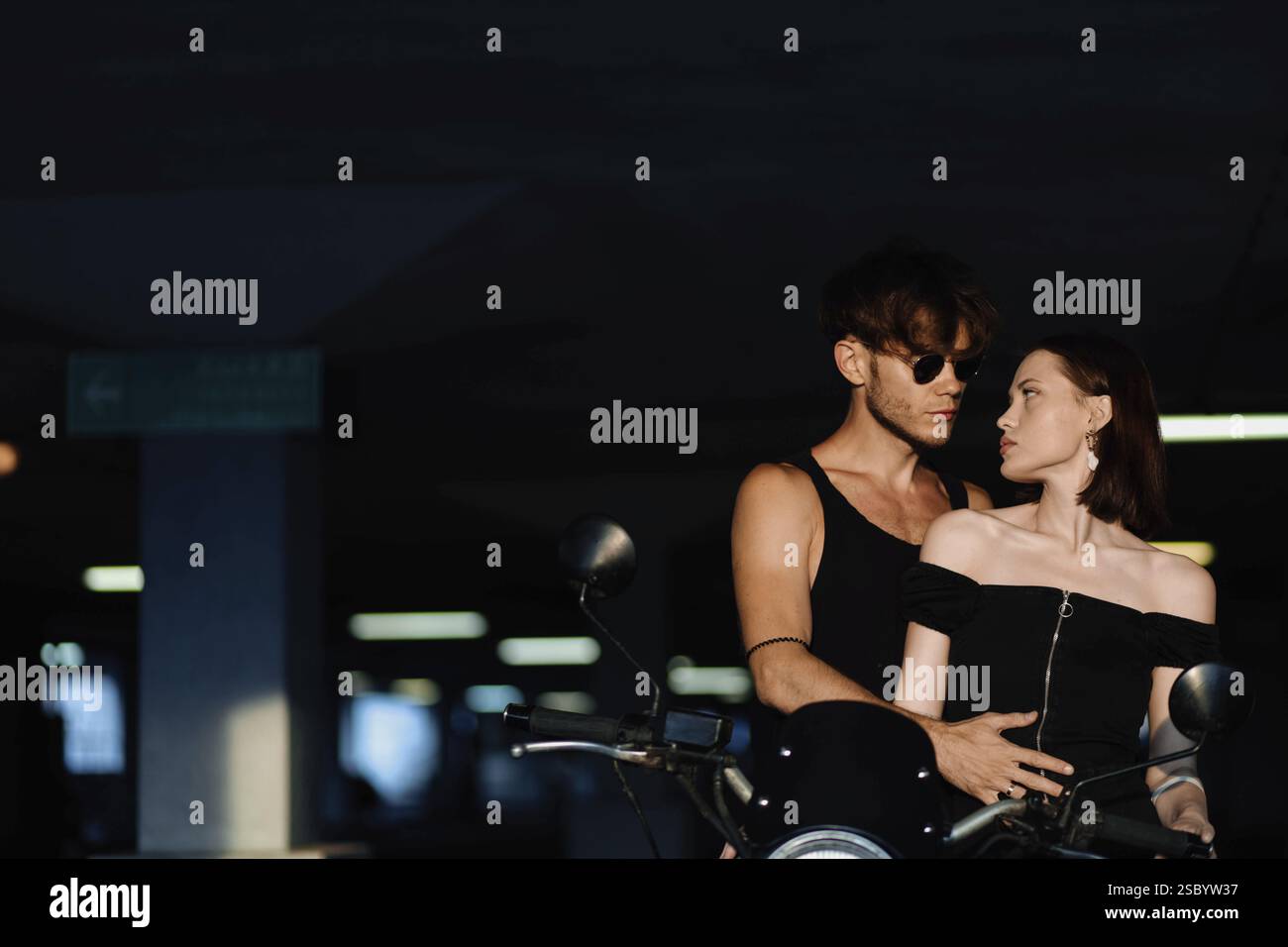 Pair on a motorcycle, wearing black, sharing an intimate glance in ...