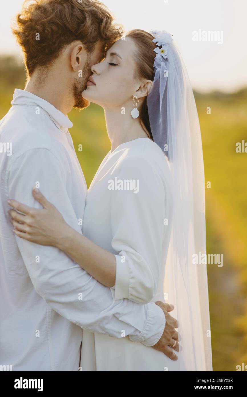A couple shares a tender kiss, enveloped in delicate sunlight and ...