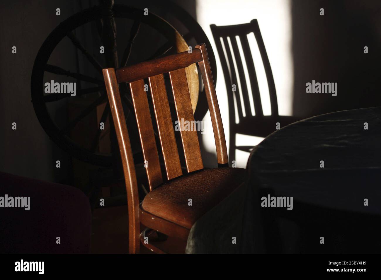 A wooden chair casting shadows in a dimly lit room with strong ...