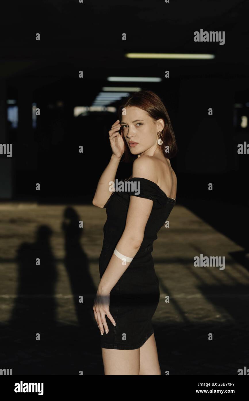 Dramatic pose of a woman in a black dress, accentuated by light and ...