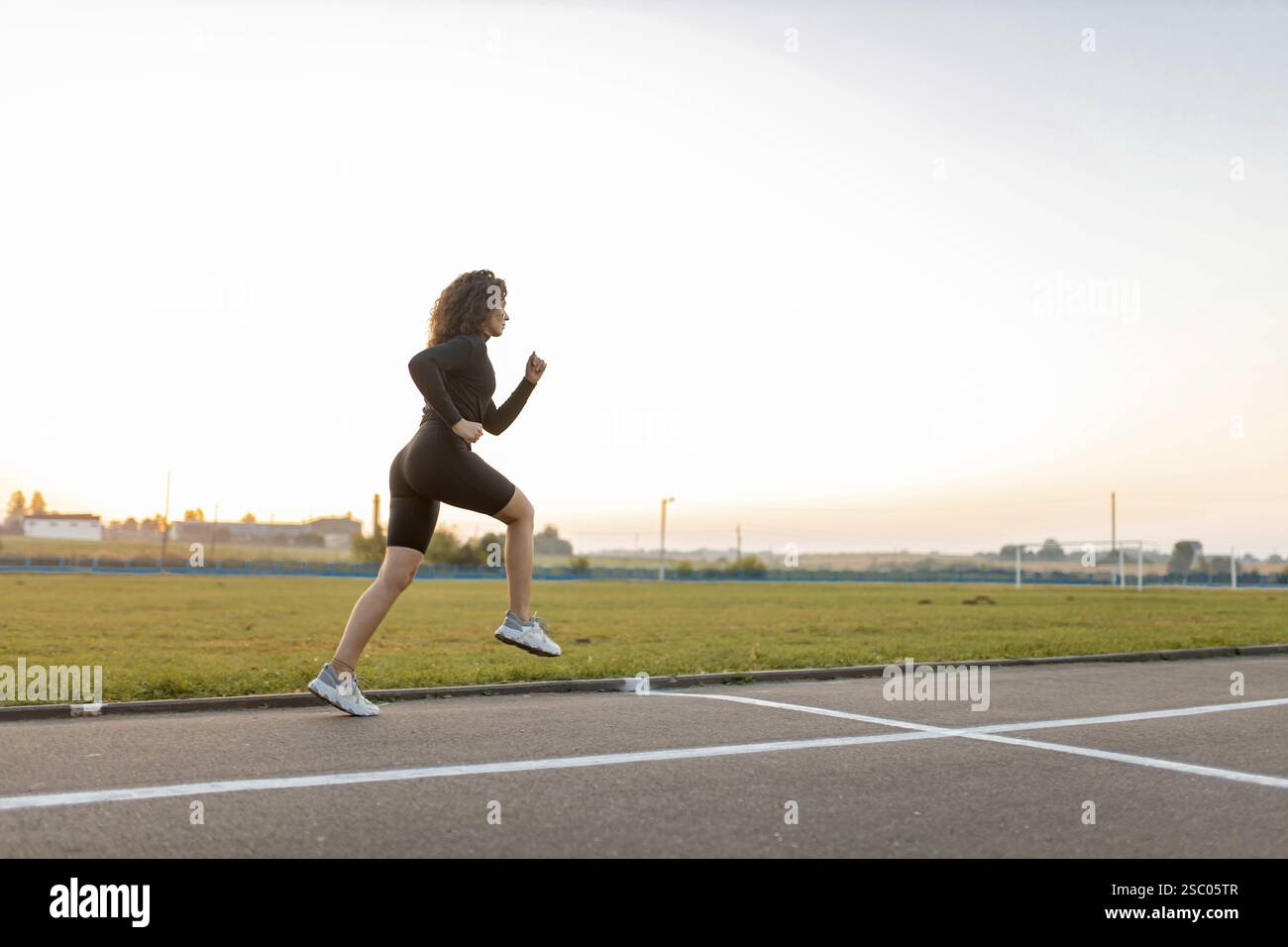 Woman running on an outdoor track at sunset in exercise attire Stock ...