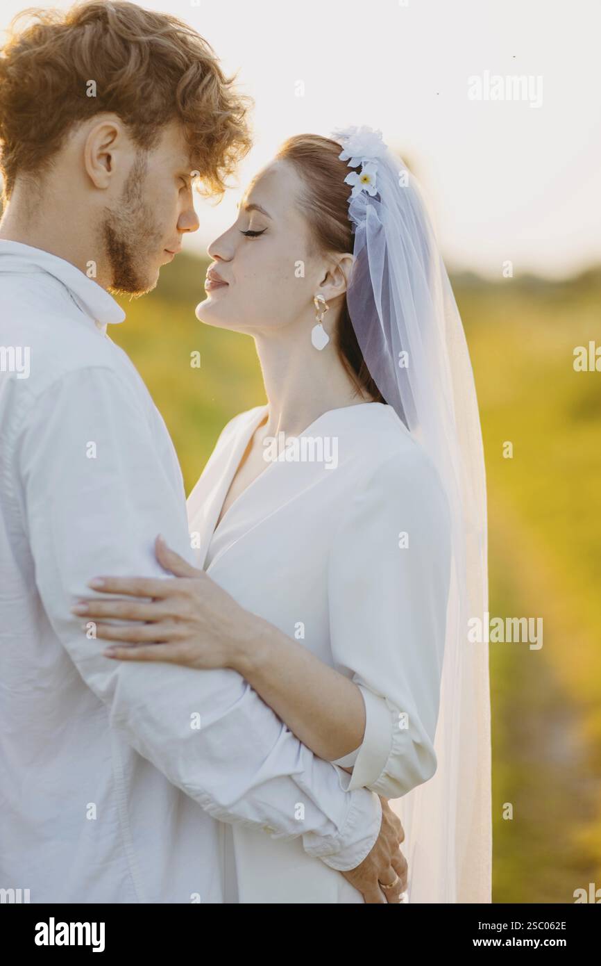A couple shares an intimate moment in a sunlit field, full of romantic ...