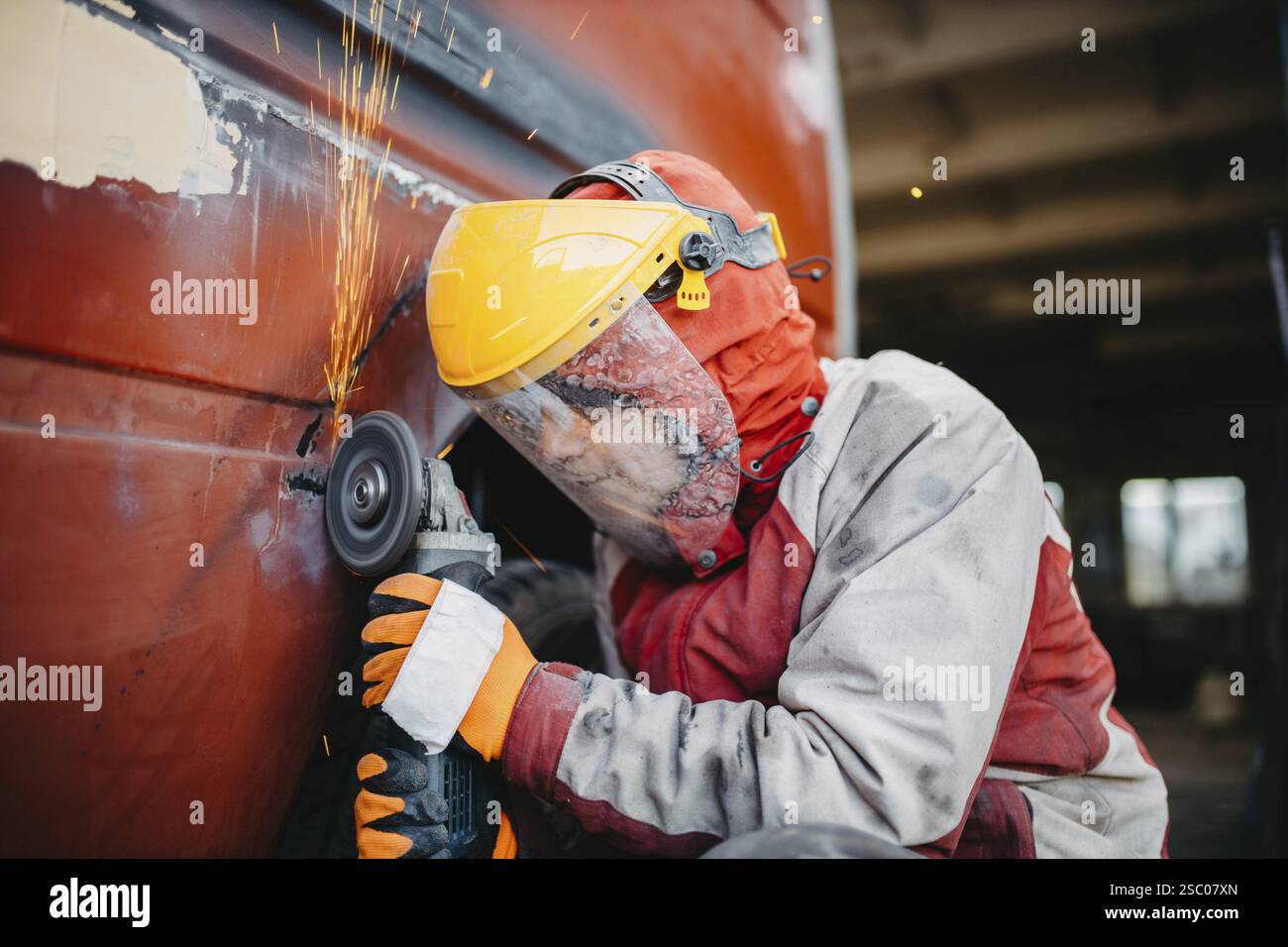A worker using a grinder on a vehicle, creating sparks Stock Photo - Alamy