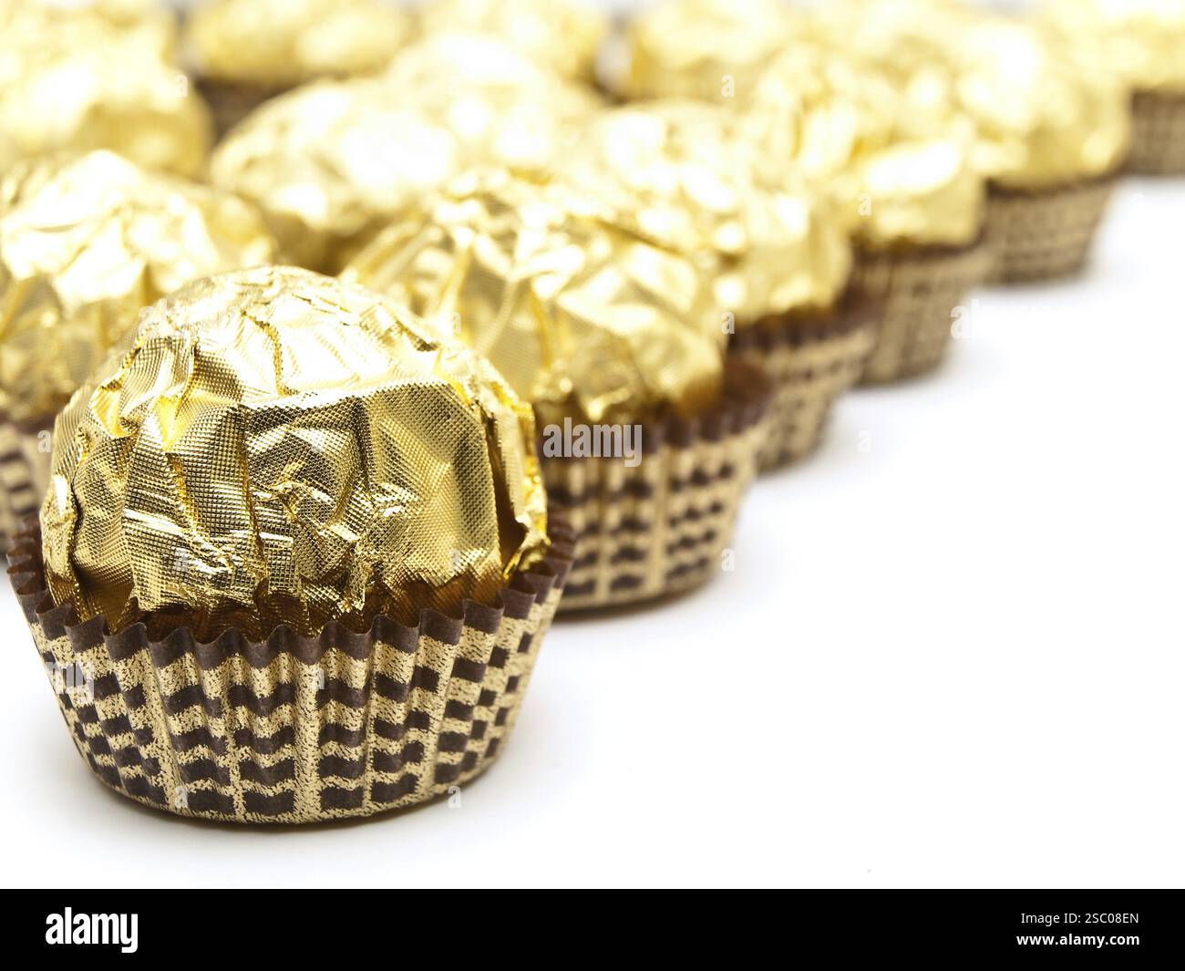 Rows of candies in gold paper over the white background Stock Photo - Alamy