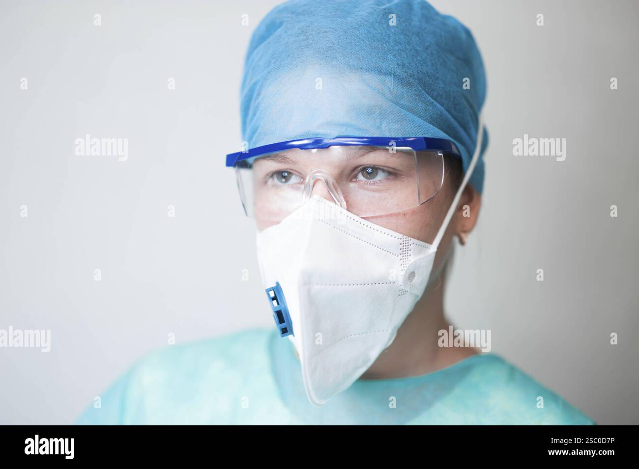 Doctor in light blue protective gear with a face mask and goggles ...