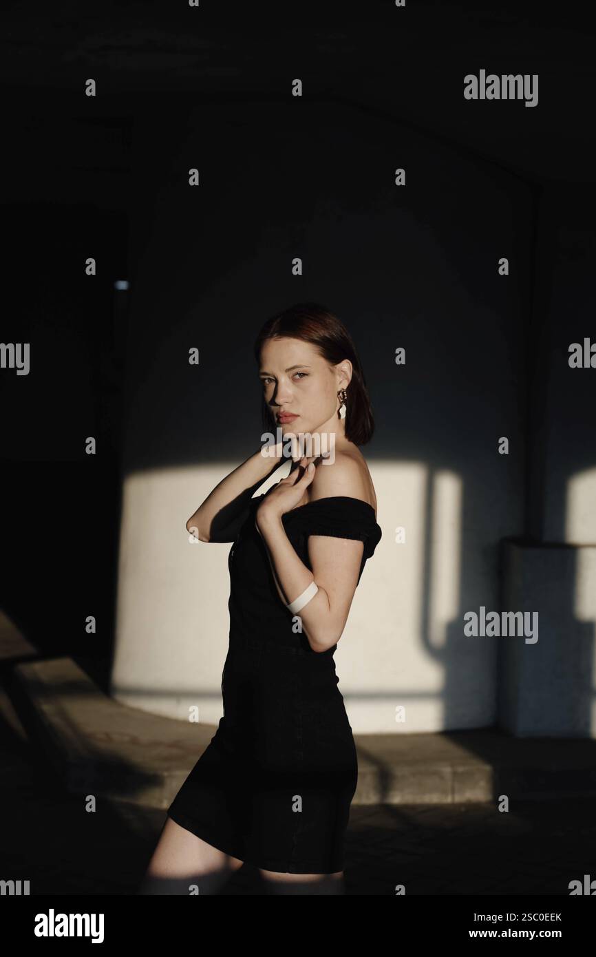 Mysterious woman in a black dress with shadows and light highlighting ...