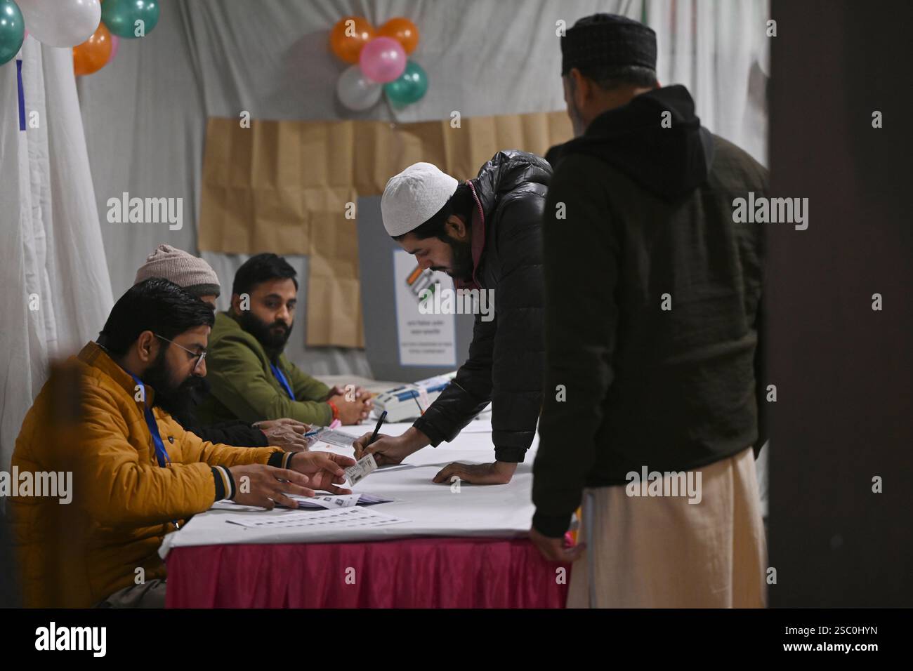 A Muslim man signs to take a voting slip for casting his vote for Delhi ...