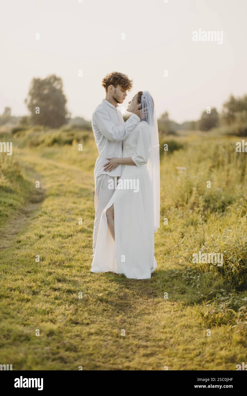 A couple stands lovingly close on a sunlit pathway, embodying a deep ...