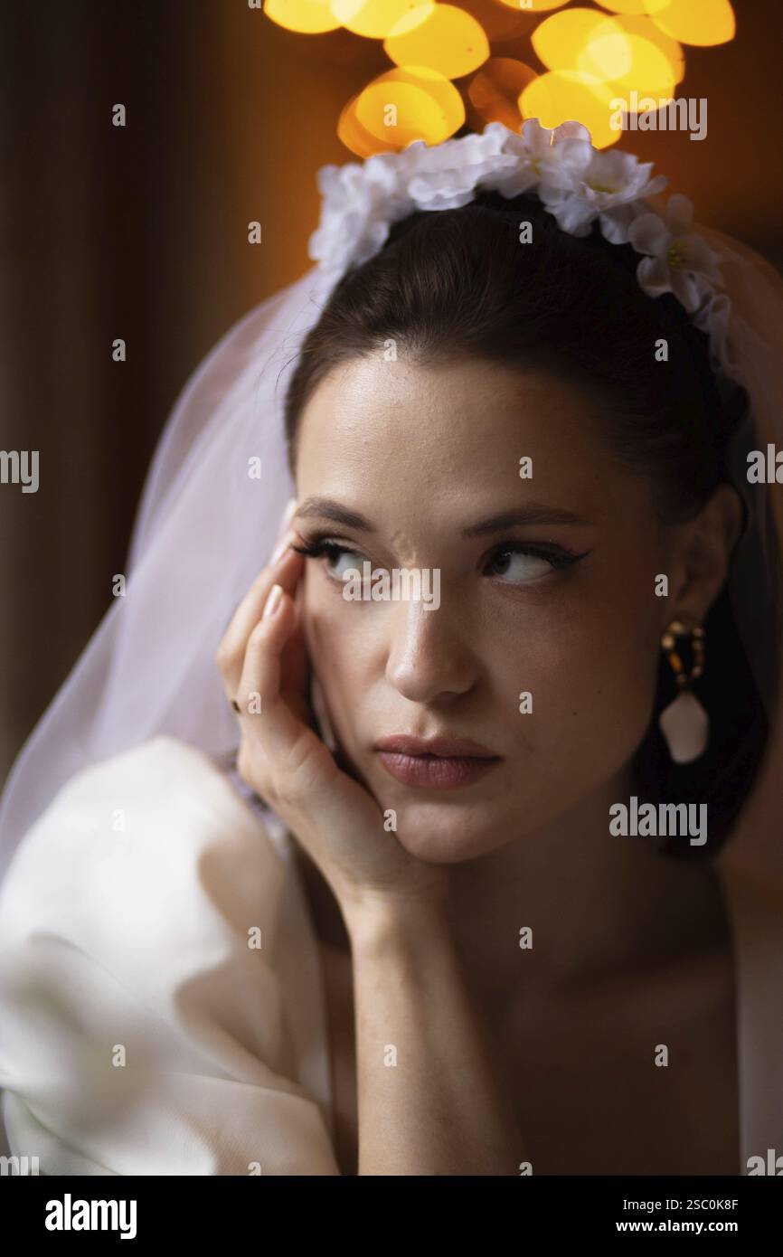 Contemplative bride with a veil, soft lighting, hand on her face, with ...