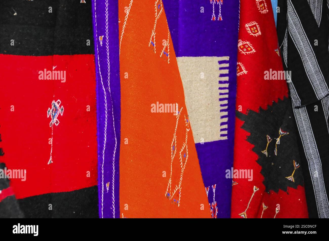 Bright, patterned fabrics in vivid colours hang side by side ...