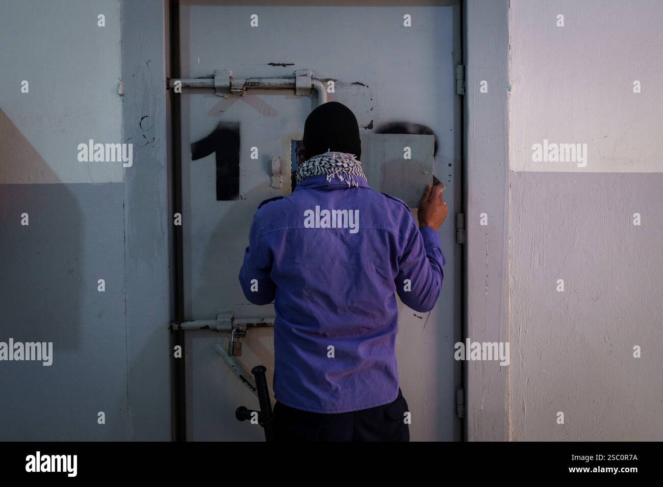 A guard opens the wicket to speak with inmates inside the Syrian ...