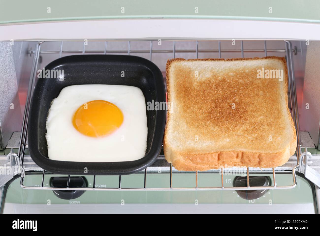 close up of baked golden toast and fried egg in a toaster oven on white ...