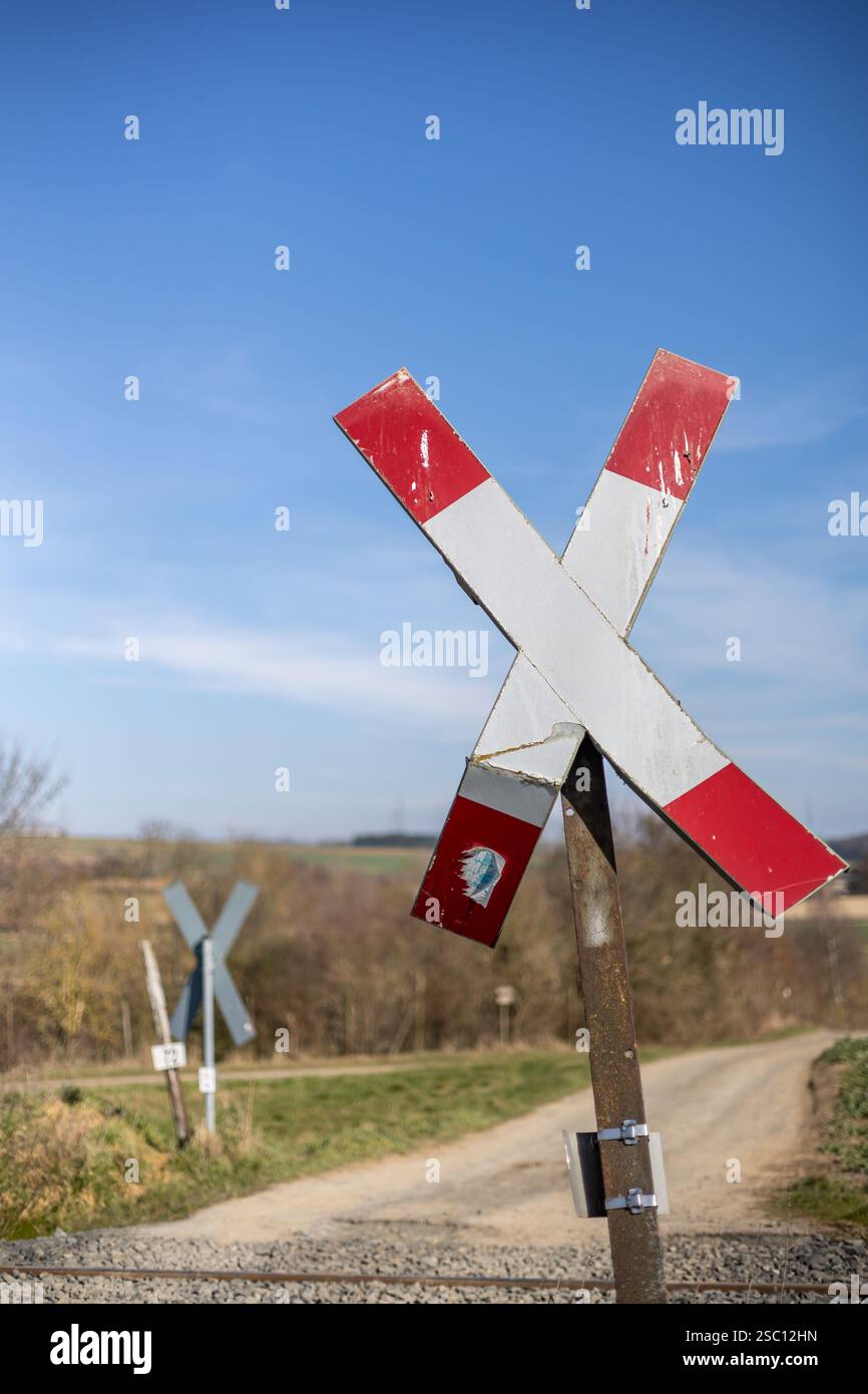 A partly bended railway crossing sign in red and white marks a dirt ...