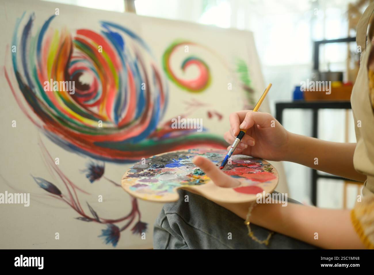 Close up of female artist mixing paint on a palette while working on ...