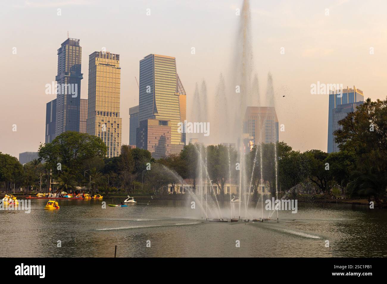 Evening in Lumpini Park with a fountain and modern skyscrapers in the ...