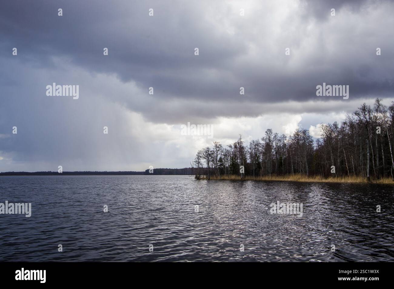 Dramatic storm over a dark lake. Ominous clouds and choppy water create ...