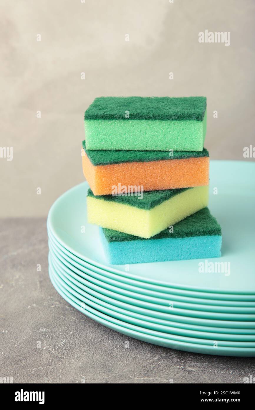 Cleaning sponge with plate on grey concrete background. Vertical photo ...