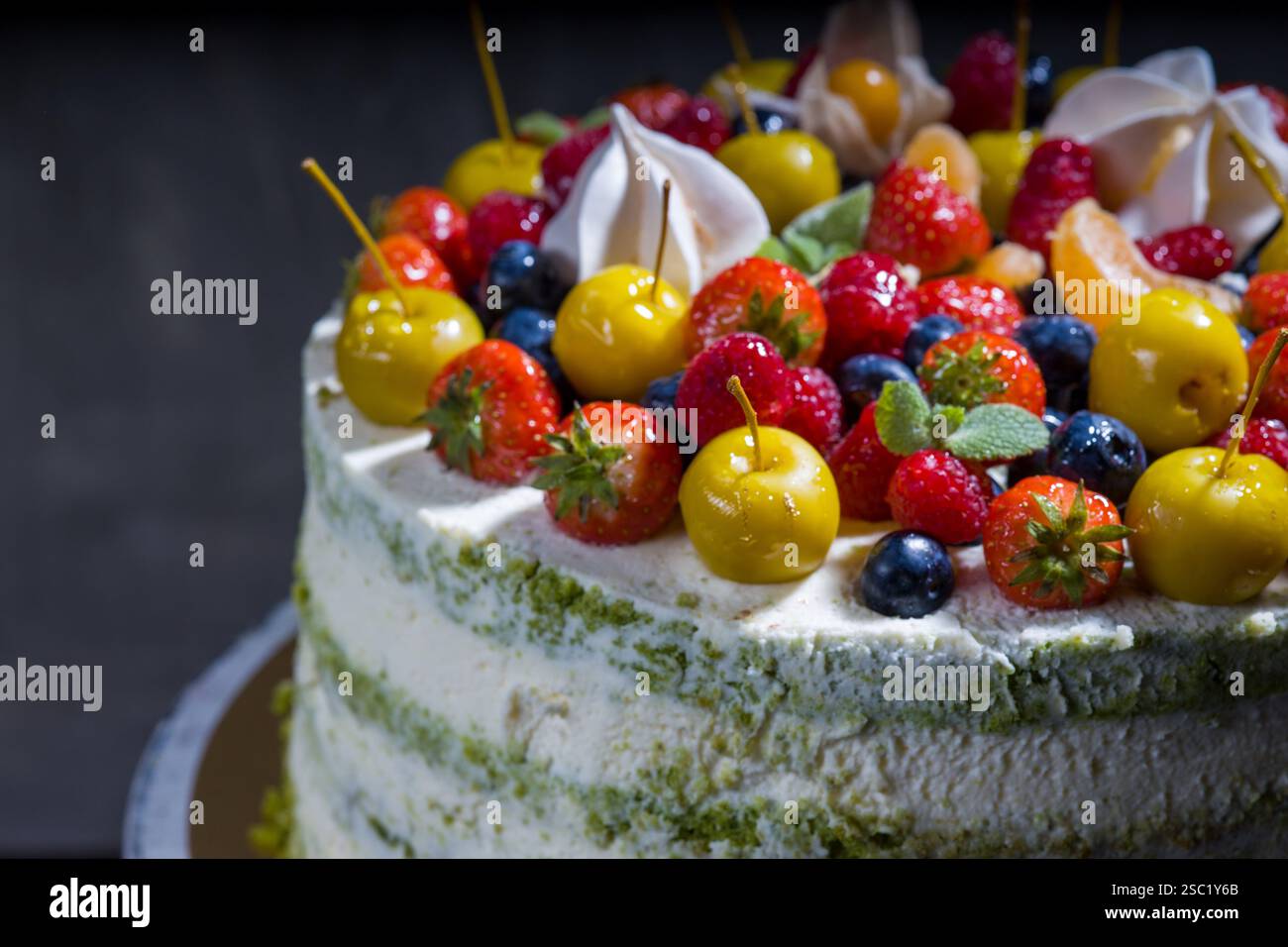 Colorful layer cake with pistachio frosting and fresh fruit toppings ...