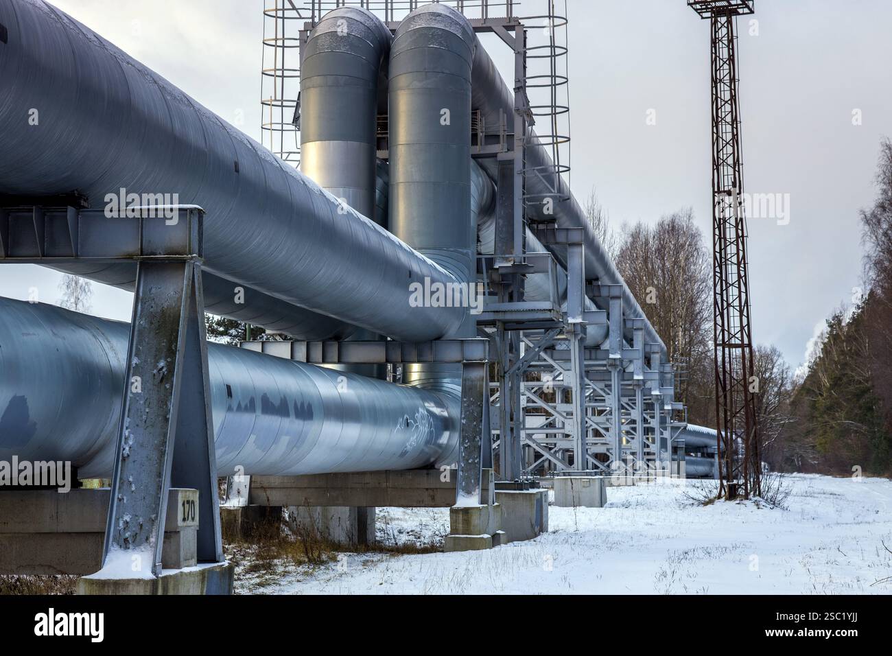 Large industrial pipes on an elevated metal structure in a snowy ...