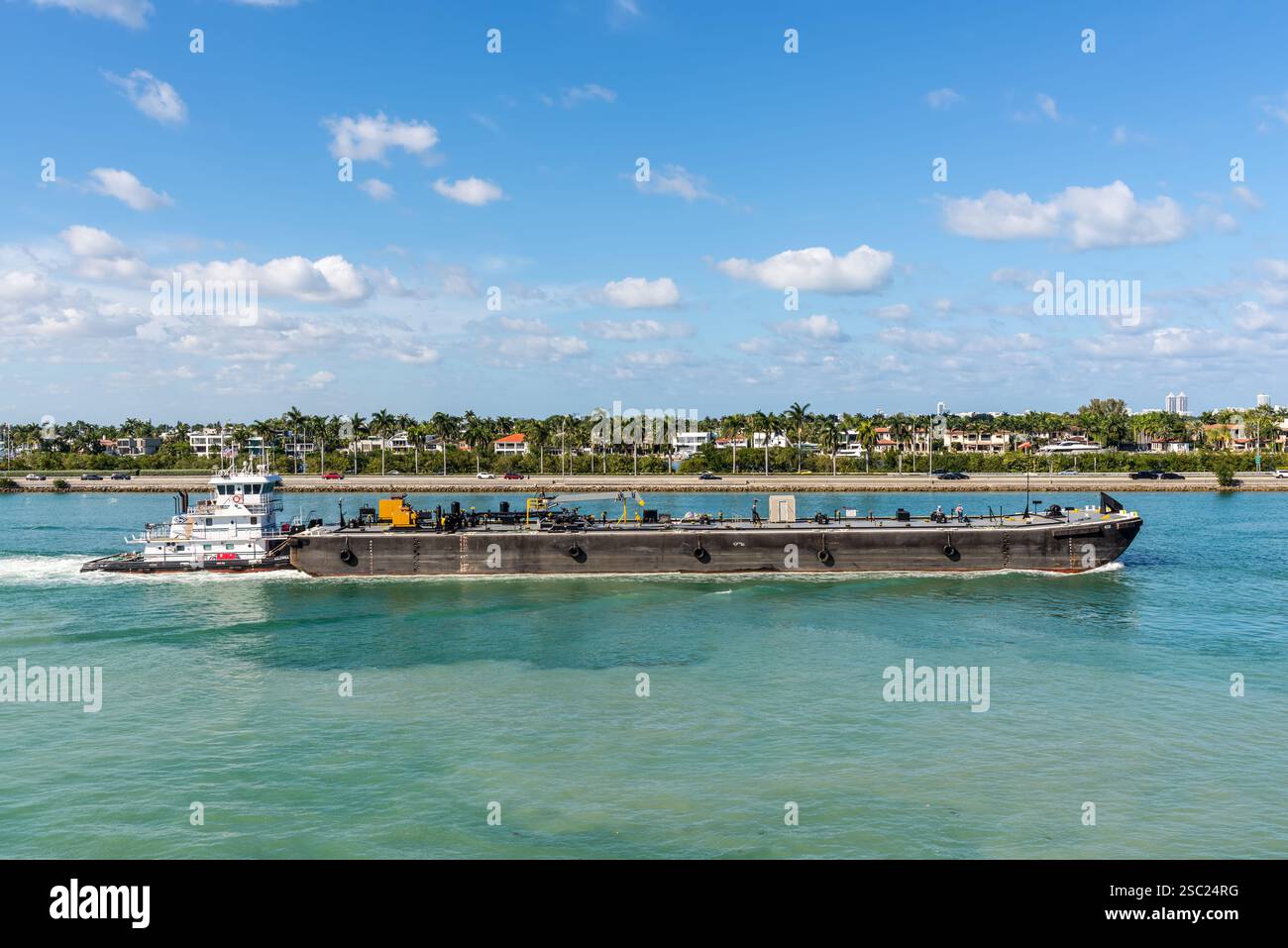Miami, FL, USA - March 31, 2024: Tug boat pushing a heavy industrial ...