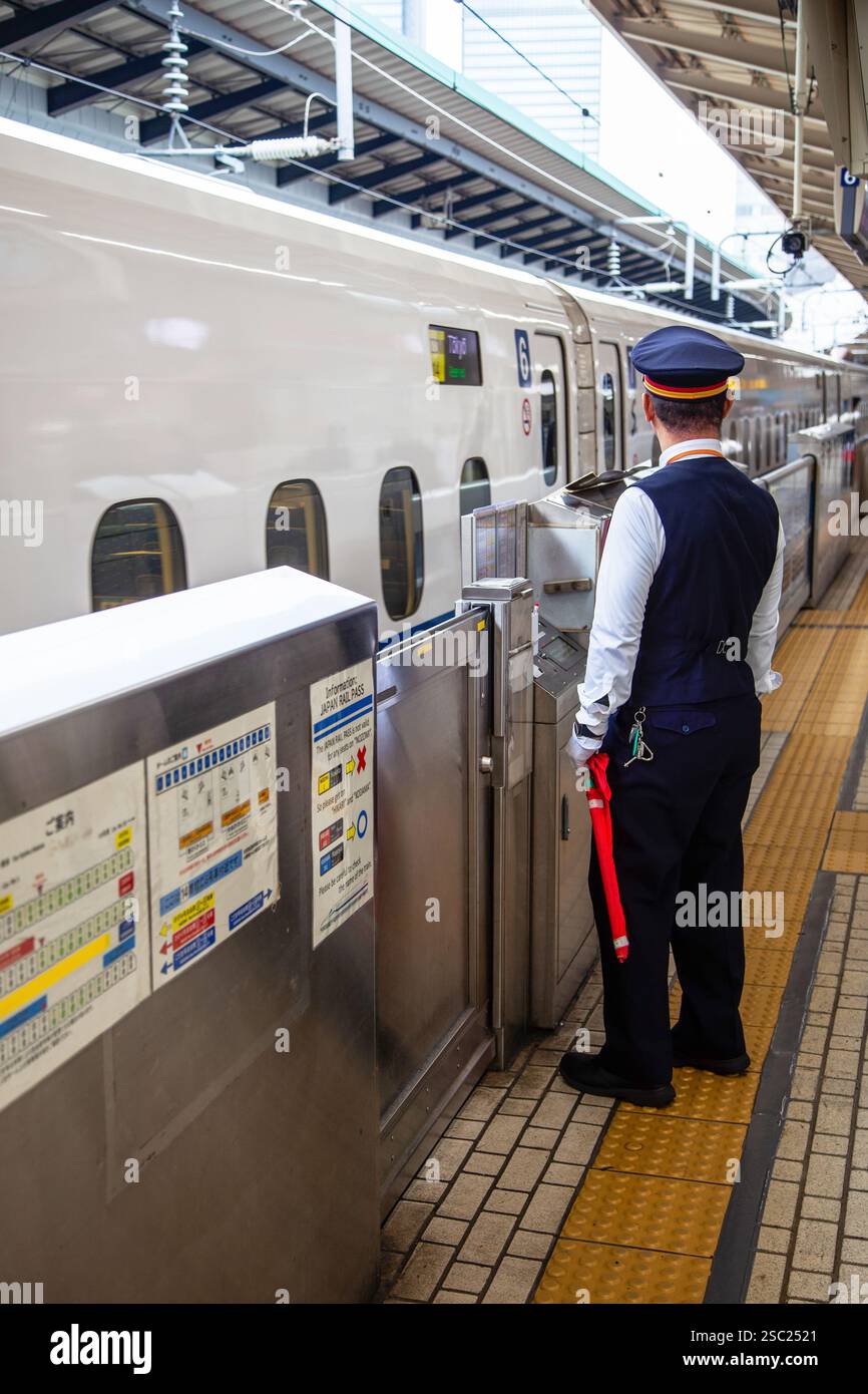 Station staff on the platform of the Shinkansen train at Shin-Osaka ...