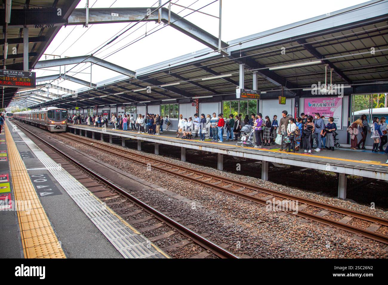 Japanese train approaching at Osakajo-koen station with many passengers ...