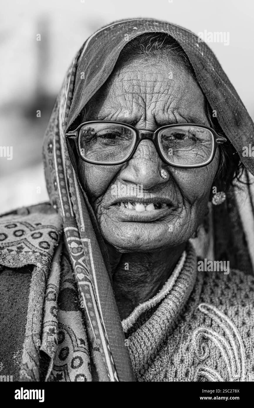 An elderly woman devotee, wearing glasses, her face a portrait of grace ...